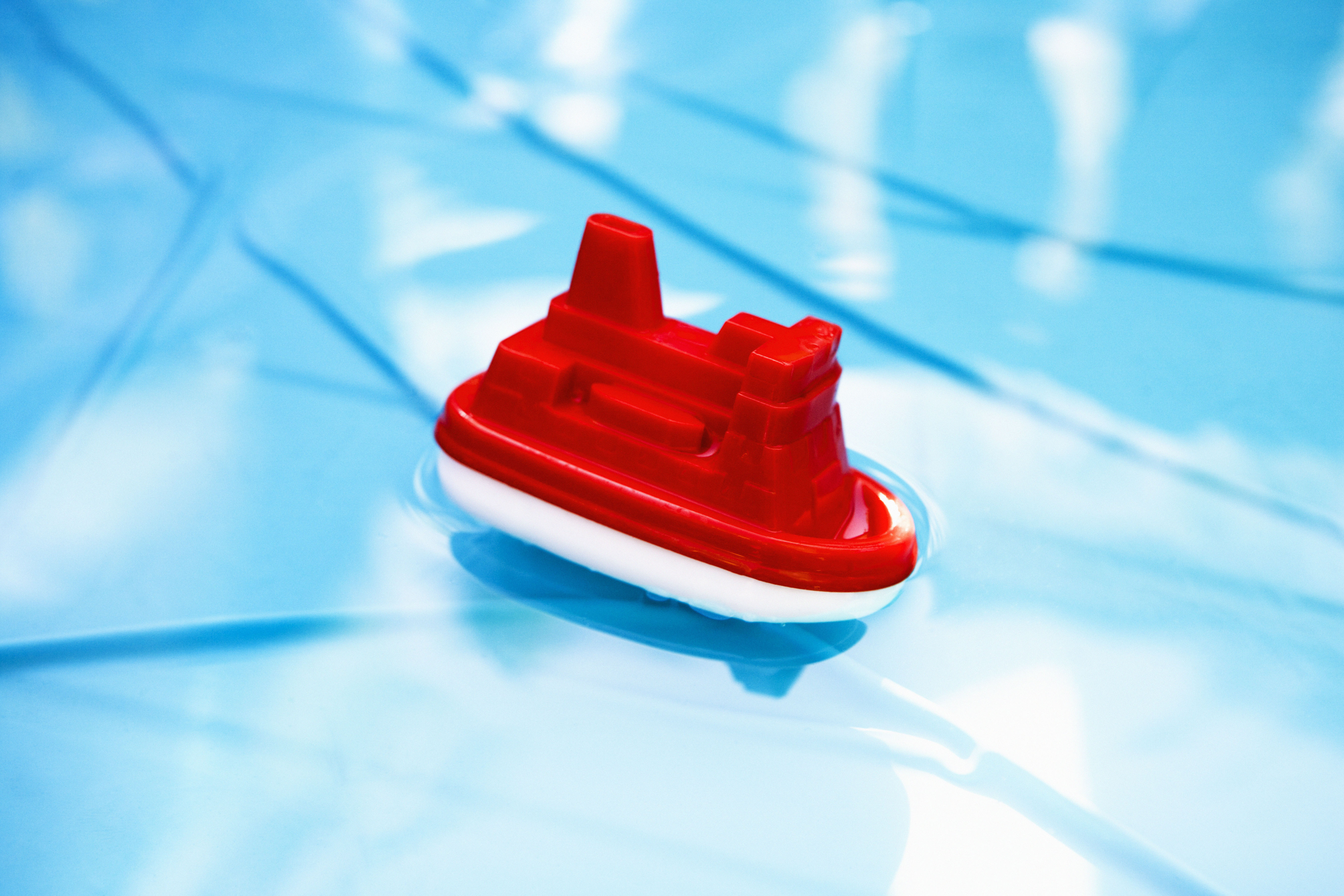 A red plastic boat floating in a swimming pool. | Brighter Thinking ...