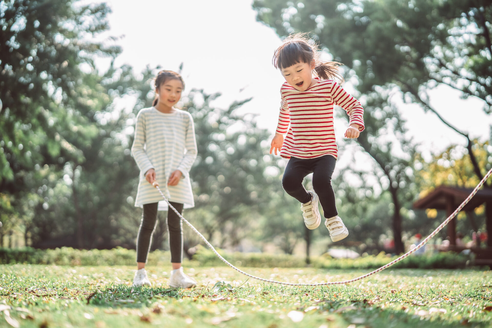 Young family jumping rope joyfully on the lawn - World of Better ...