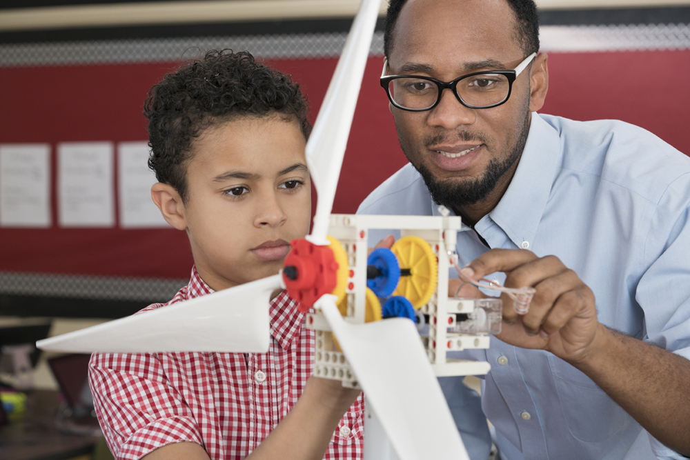Teacher helping student with model wind turbine | Brighter Thinking ...